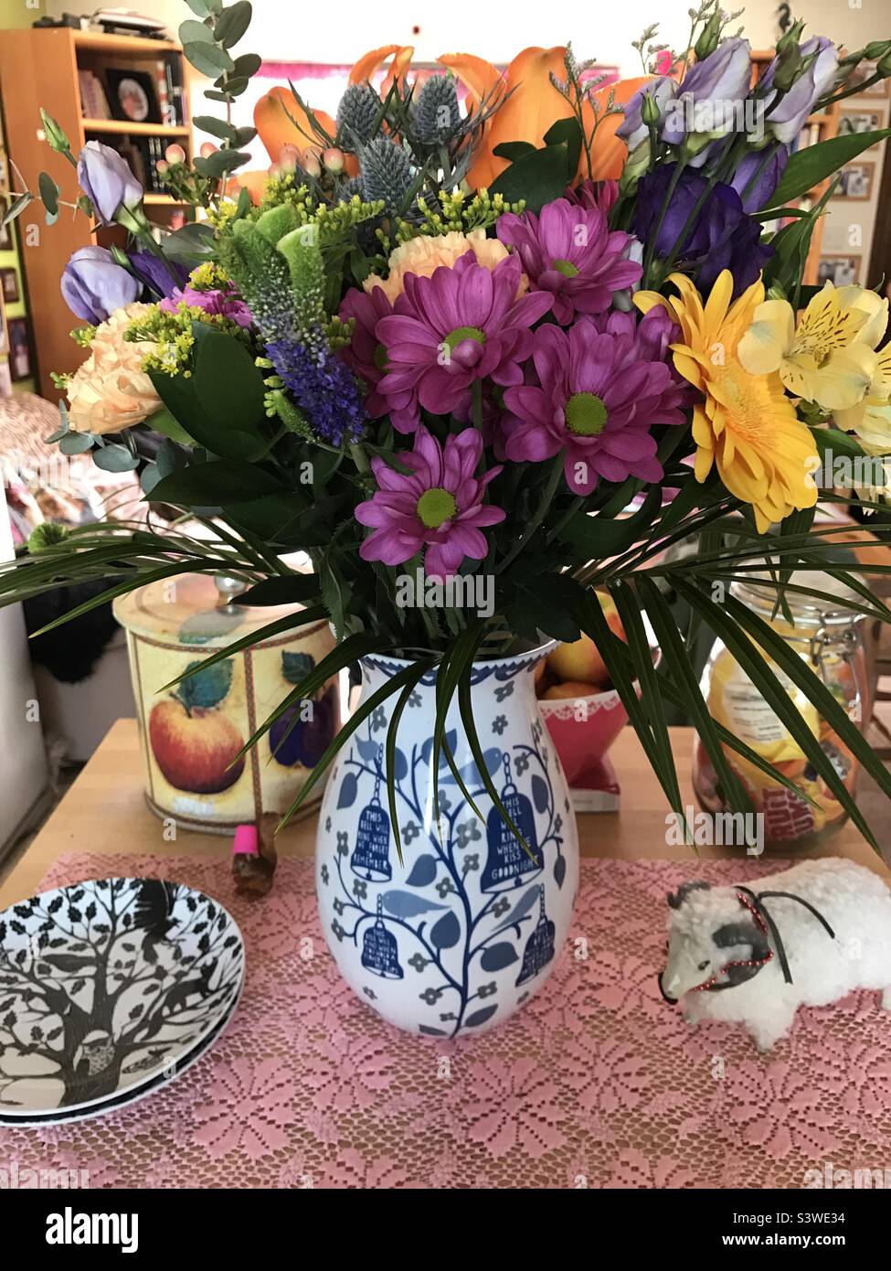 Very bright flowers in a Rob Ryan vase next to a decorative plate and ...