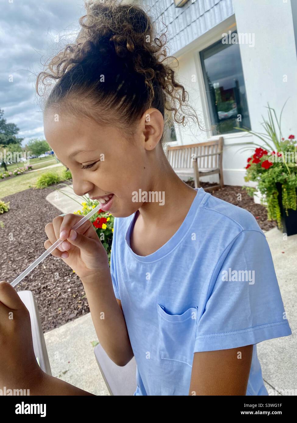 Girl chewing on straw Stock Photo - Alamy
