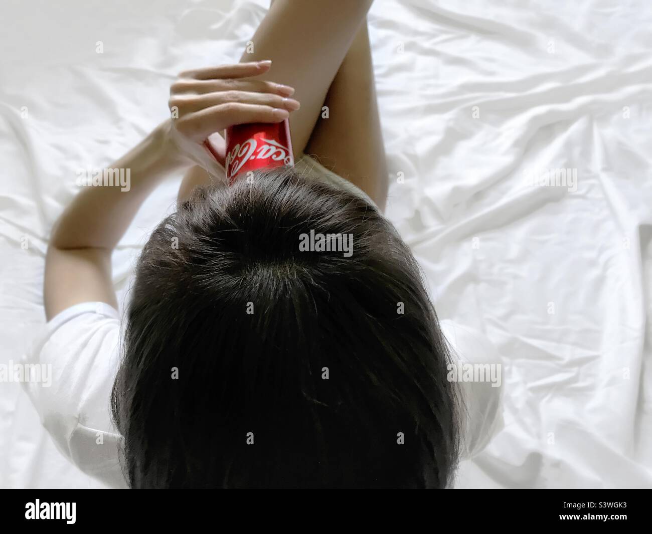 Young woman with long hair drinking coca cola in white bed Stock Photo ...