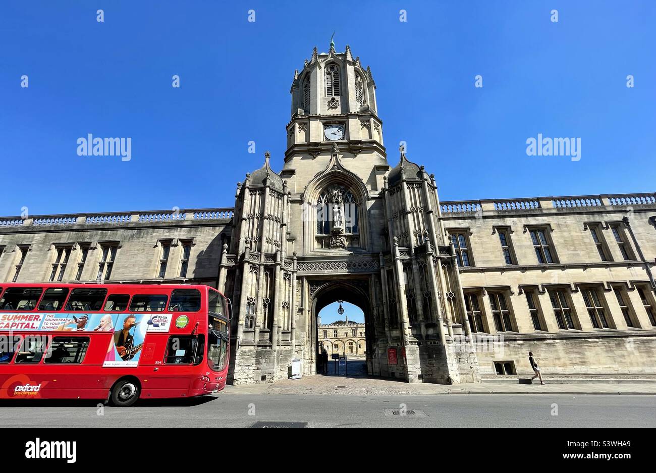 Red bus passing by Tom Tower, also known as Great Tom or Tom Quad. It ...