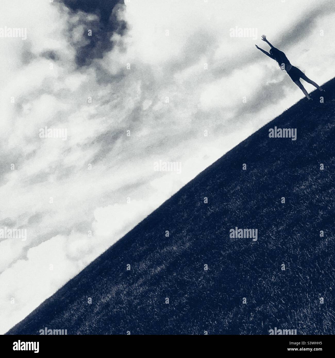Silhouette of girl on slanted hill with clouds stretching arms and ...
