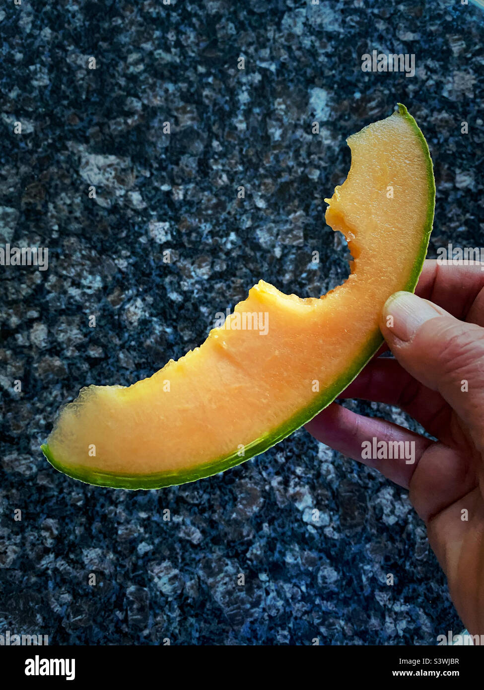 Slice of melon with a bite mark Stock Photo - Alamy