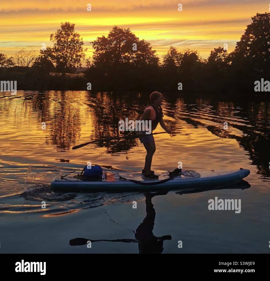 Paddle boarding at sunset Stock Photo - Alamy