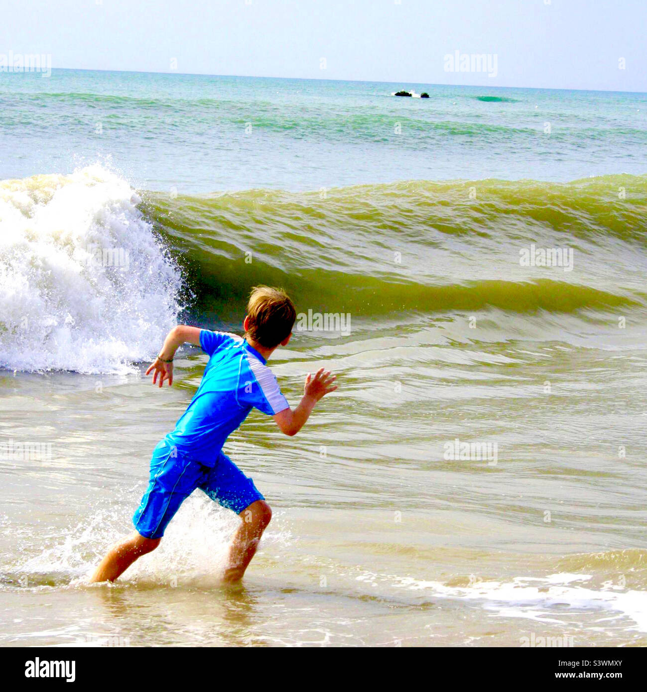 Young boy in blue, chasing the waves Stock Photo - Alamy