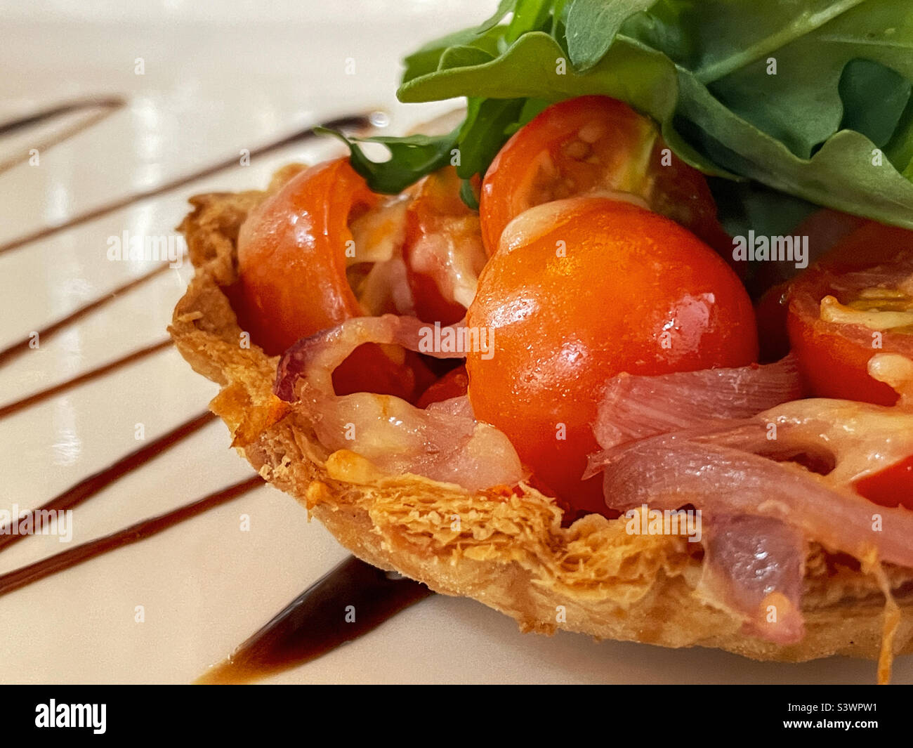 Tomato and bacon tart with rocket lettuce Stock Photo - Alamy