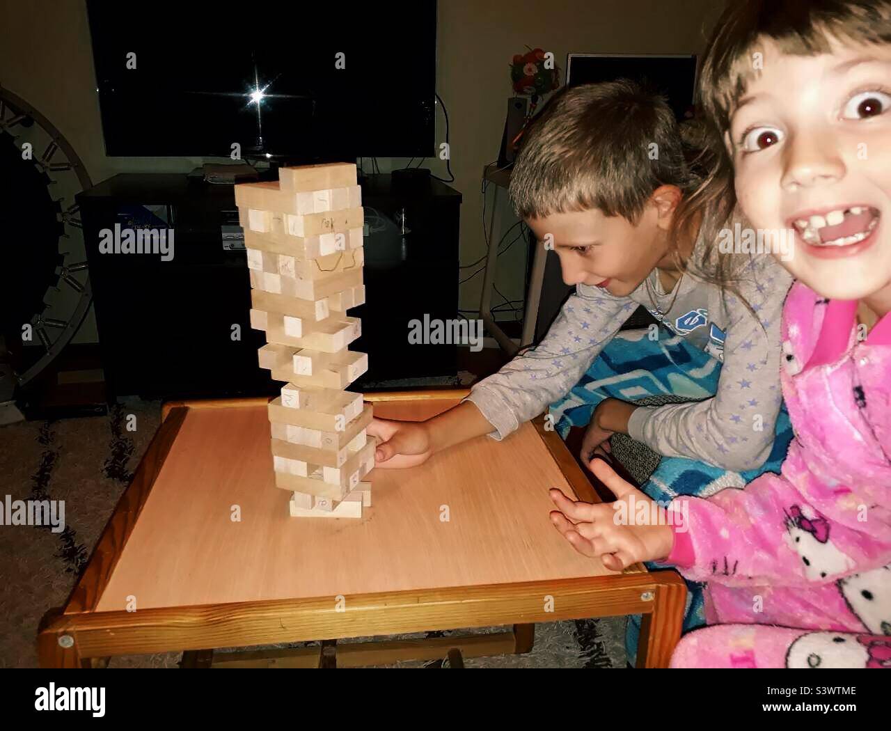 Kids playing jenga at home at night Stock Photo - Alamy