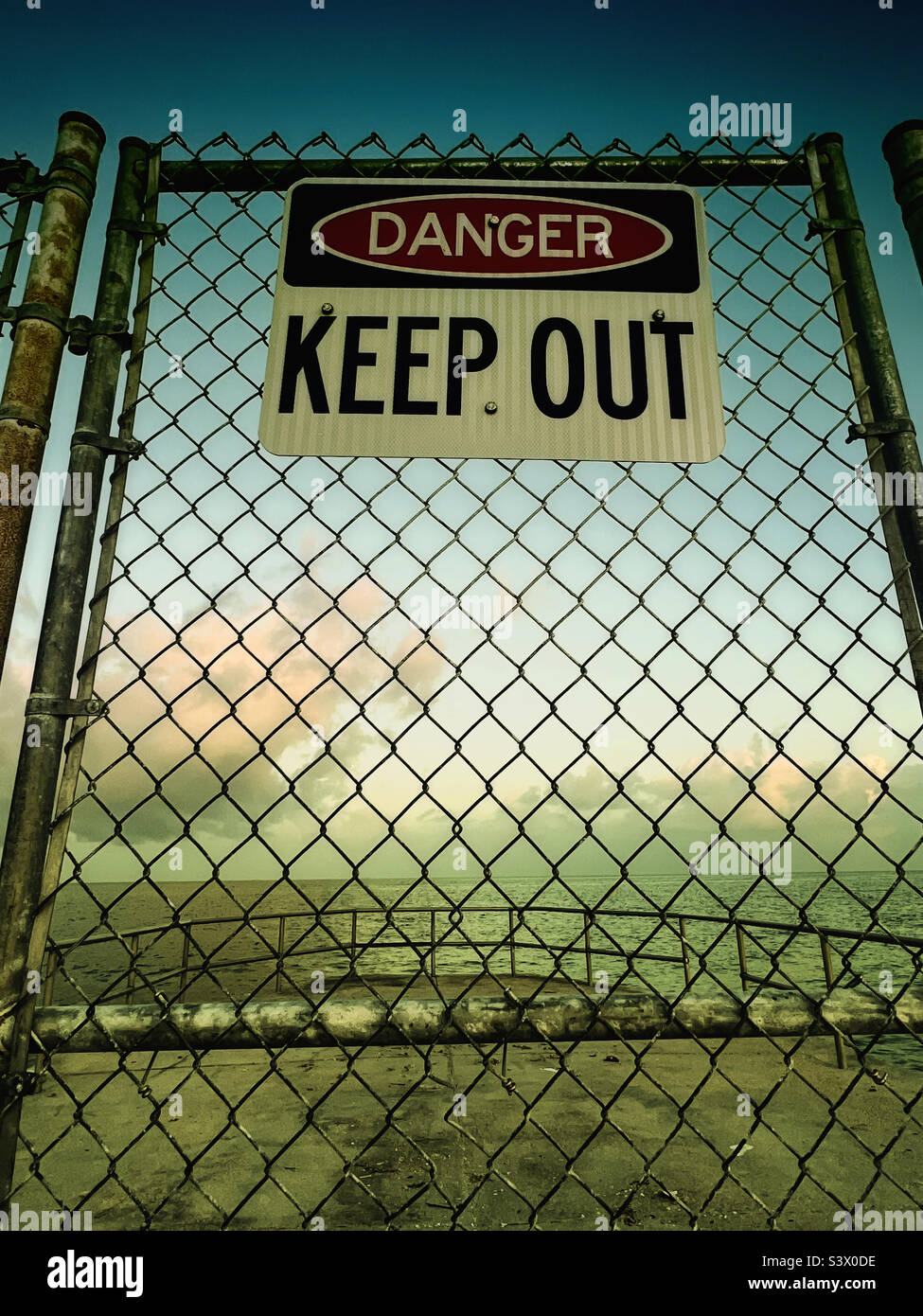 Keep out sign on fence by ocean Stock Photo - Alamy