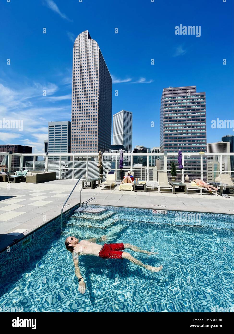 A man floating in a rooftop pool at a hotel in Denver Colorado Stock ...