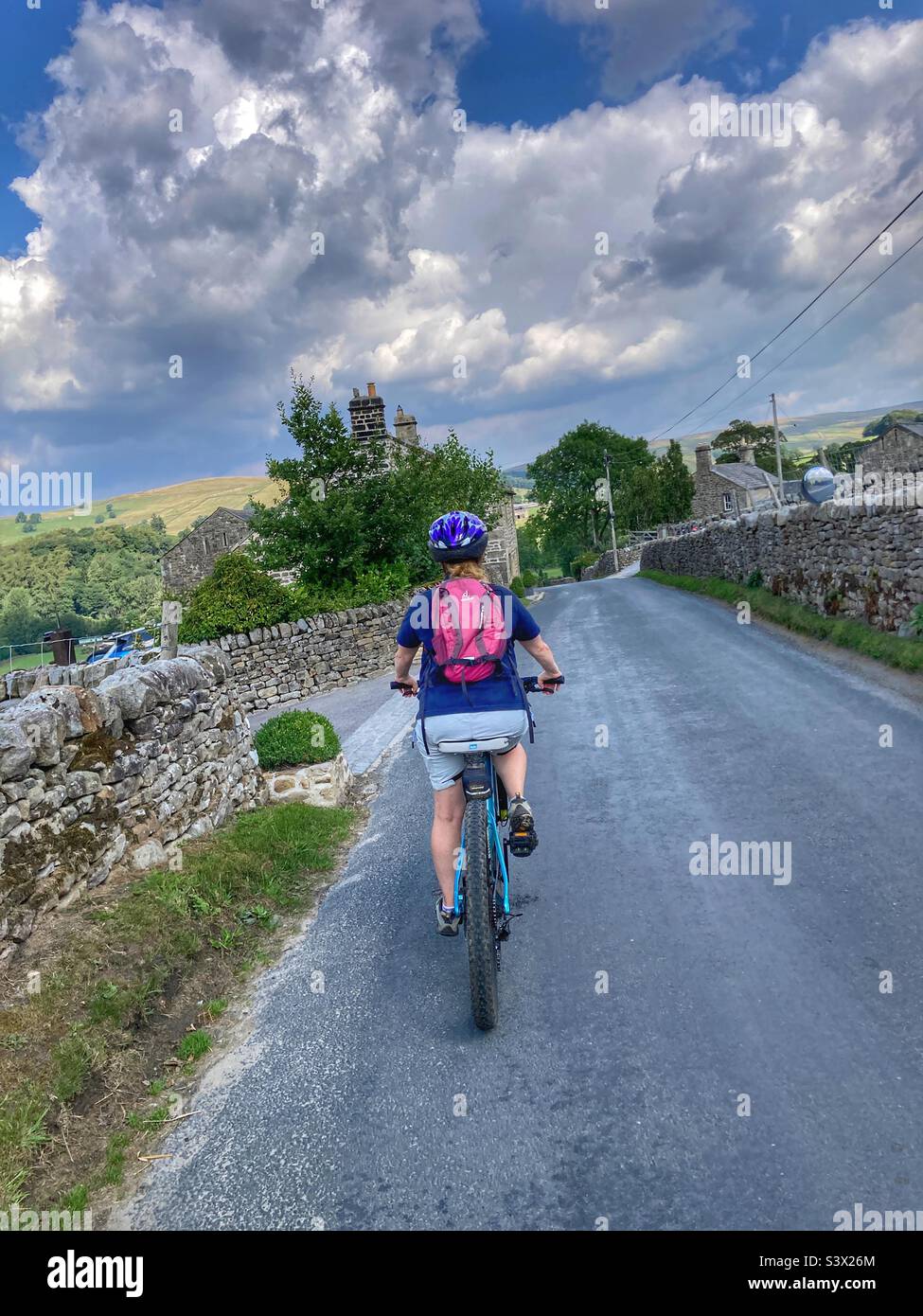 Woman cycling through Appletreewick in the Yorkshire Dales Stock Photo ...