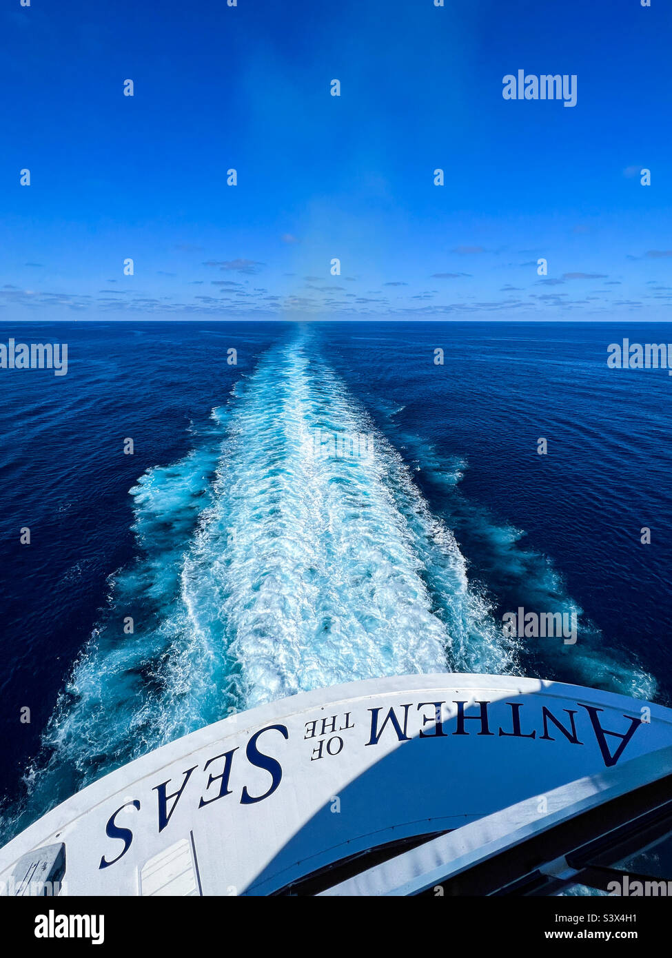Cruise ship wake stretching from the stern to the blue sky horizon ...