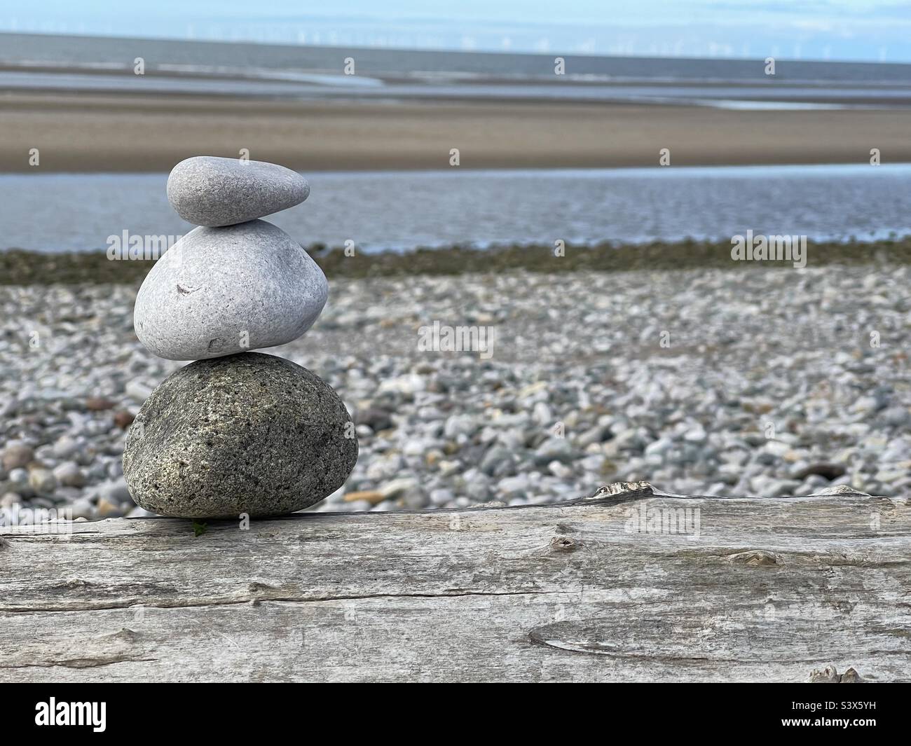A tower of rocks atop a log, with the sand and sea as a backdrop Stock ...