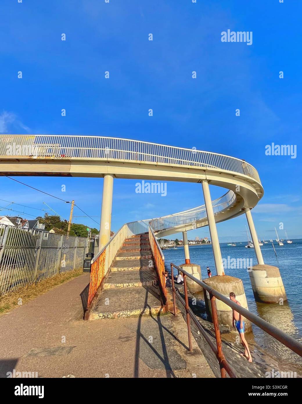 Curly whirly footbridge over the coastal railway line with supports in ...