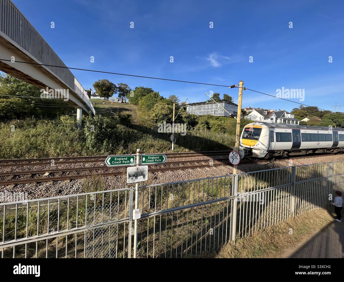 Train approaching the footbridge on the Thames estuary with footpath ...