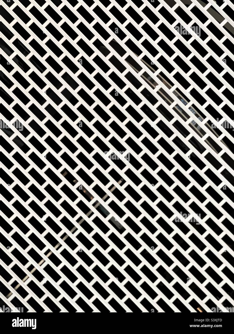 Pattern formed by the metal security grille on the entrance to a shop ...