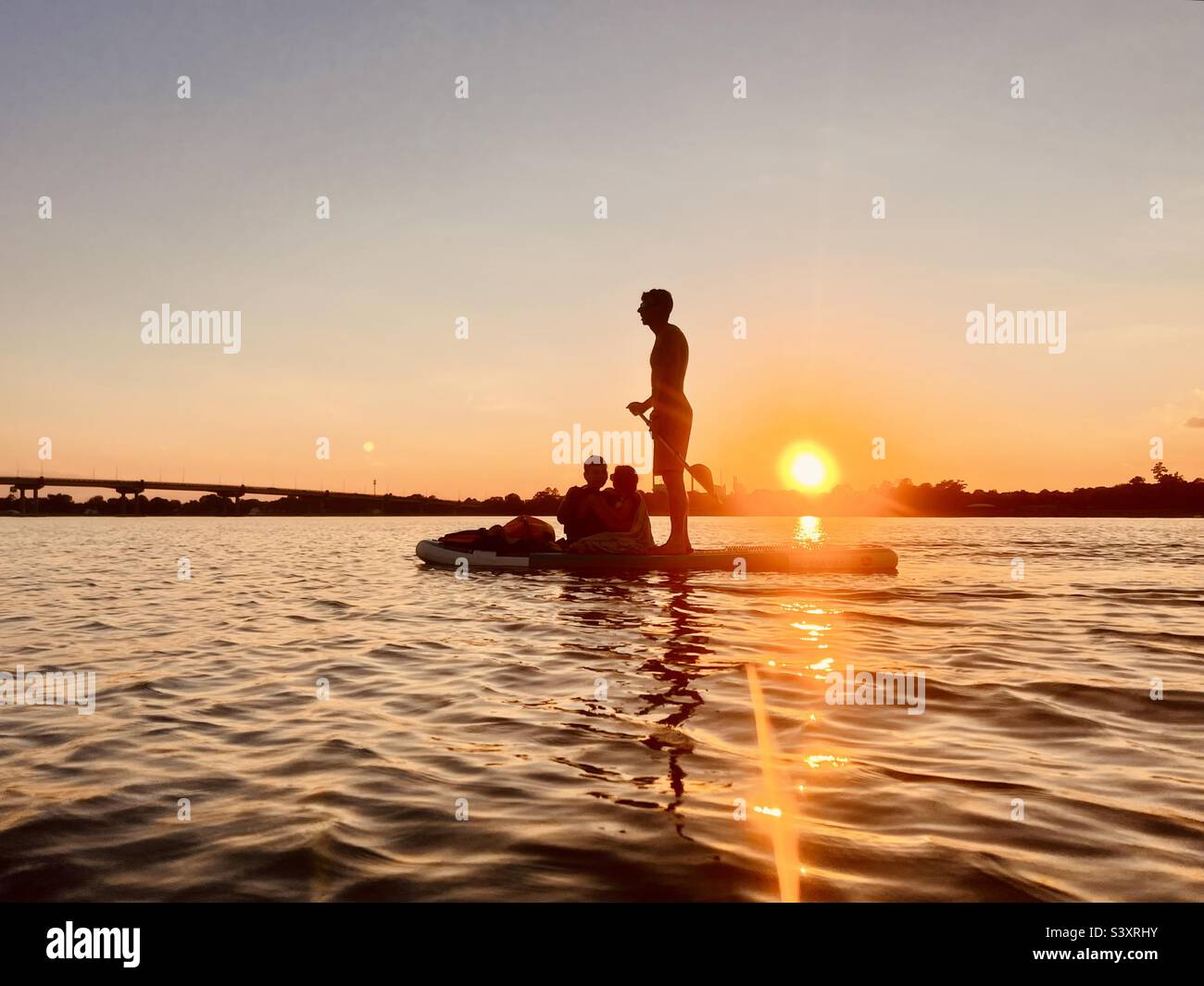 Father and children paddle boarding in the sunset Stock Photo - Alamy