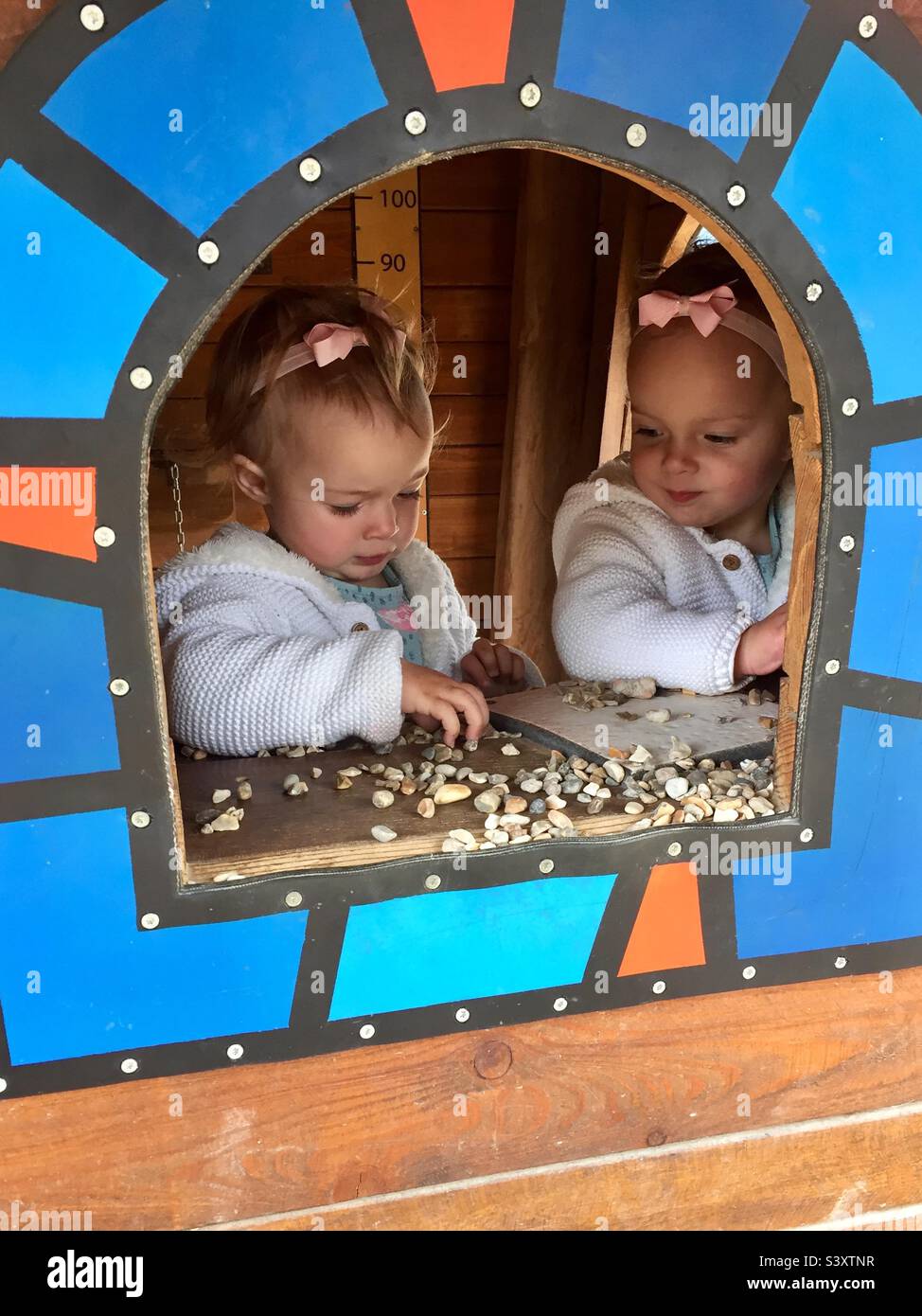 Twins girls playing with small stones Stock Photo - Alamy