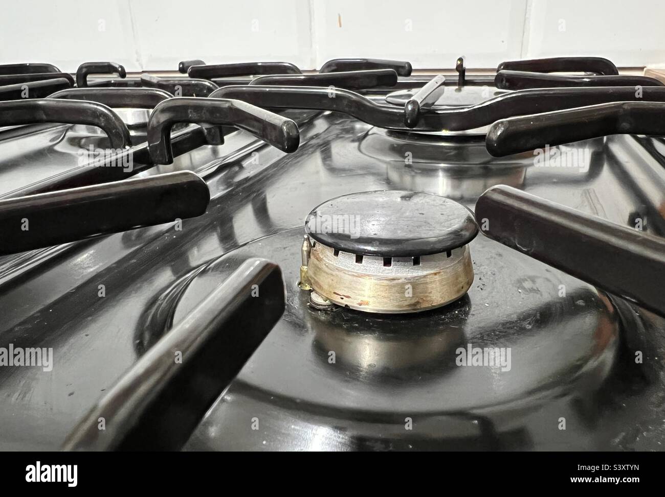 Slightly dirty gas hob, showing iron supports and white tile background ...