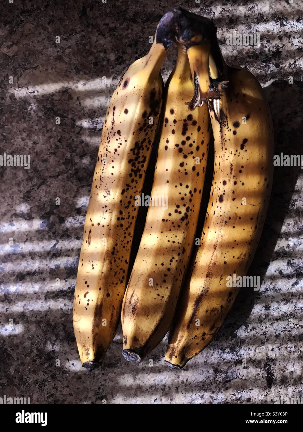 Three ripe bananas in light and shadows Stock Photo - Alamy