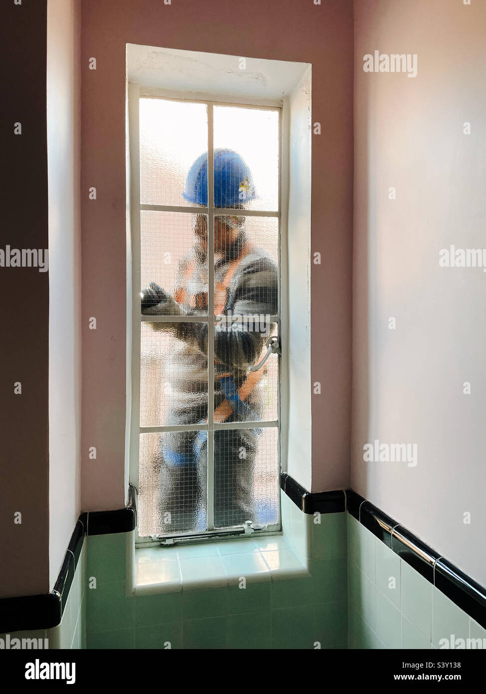 Construction worker weatherproofing the outside of a high-rise building ...