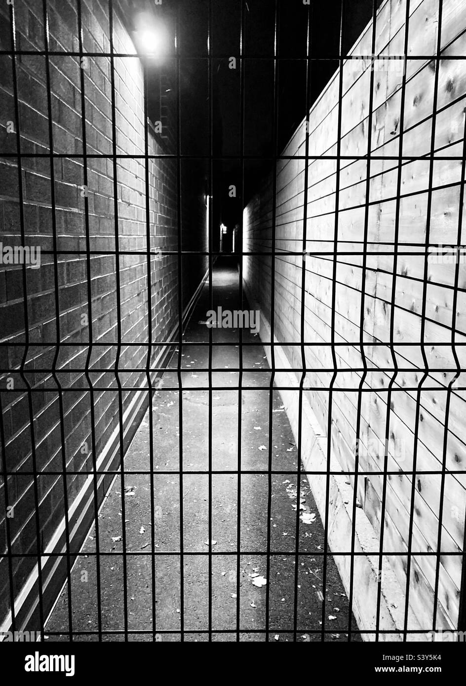 Black and white alley with a caged fence Stock Photo - Alamy