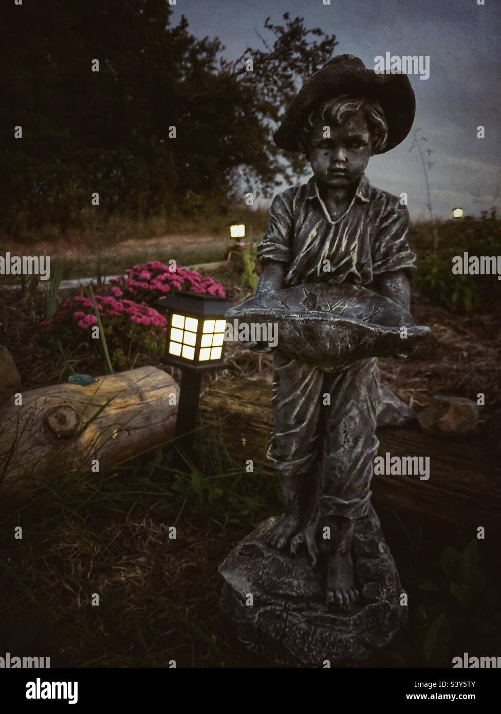 Little boy statue in garden after sundown with solar lights Stock Photo ...