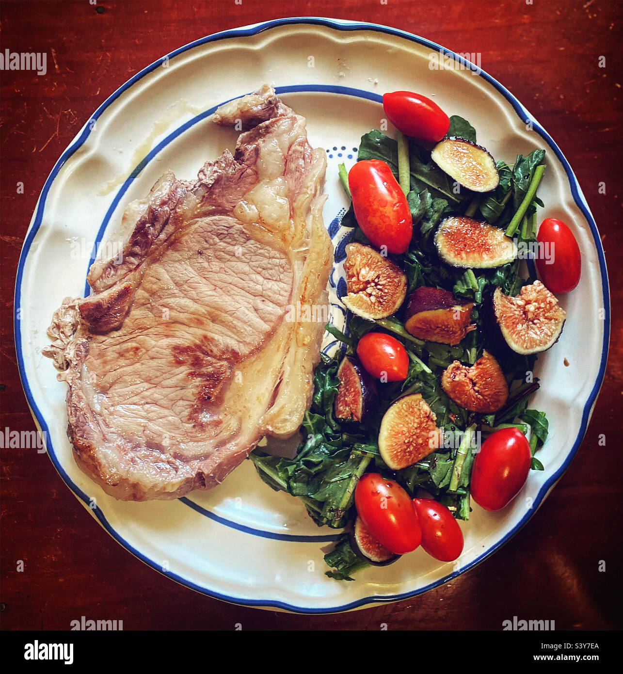 Cow meat with arugula salad with tomatoes and figs in a plate in ...