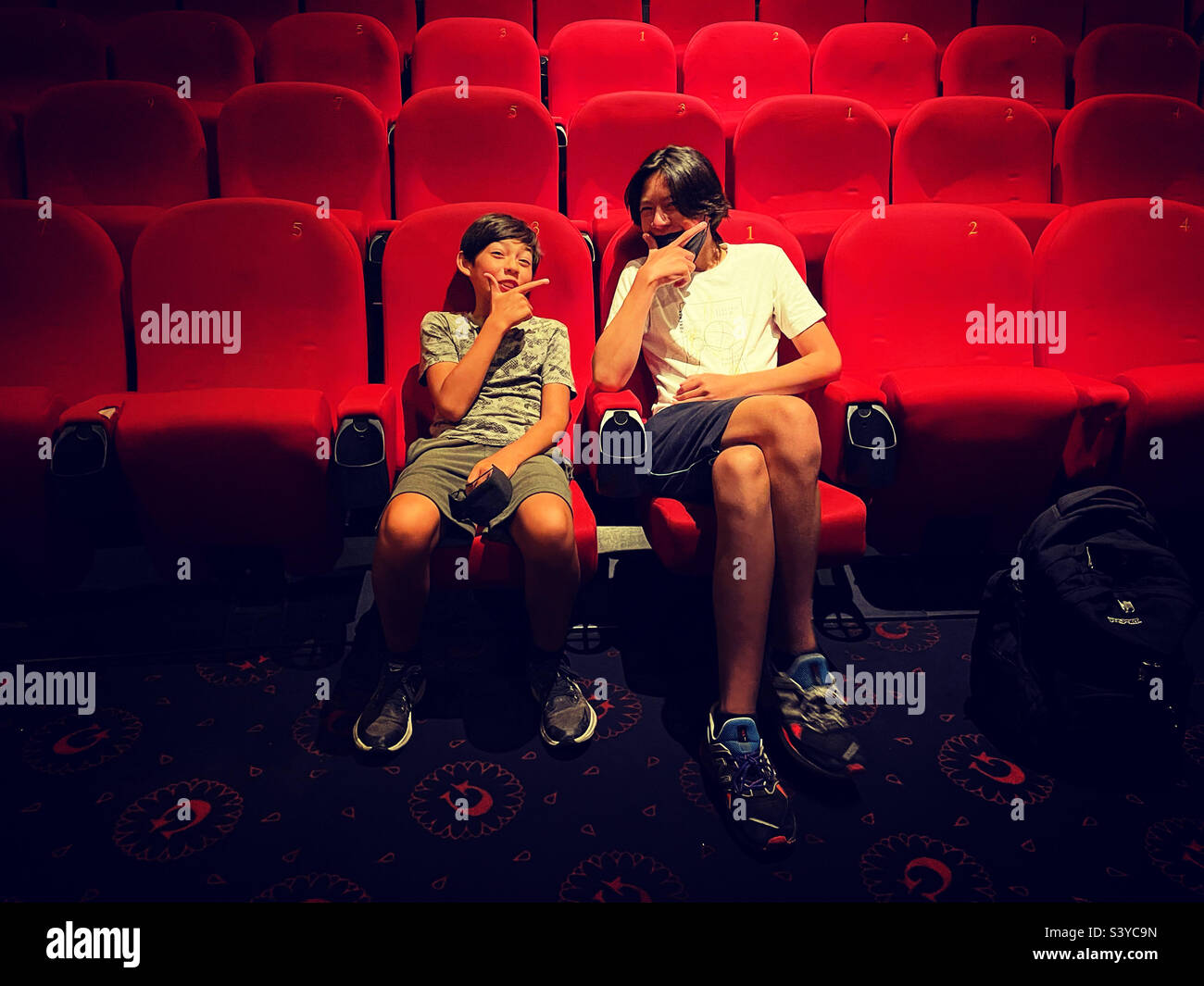 2 friends at the cinema or theater wsiting for the film to start. They ...