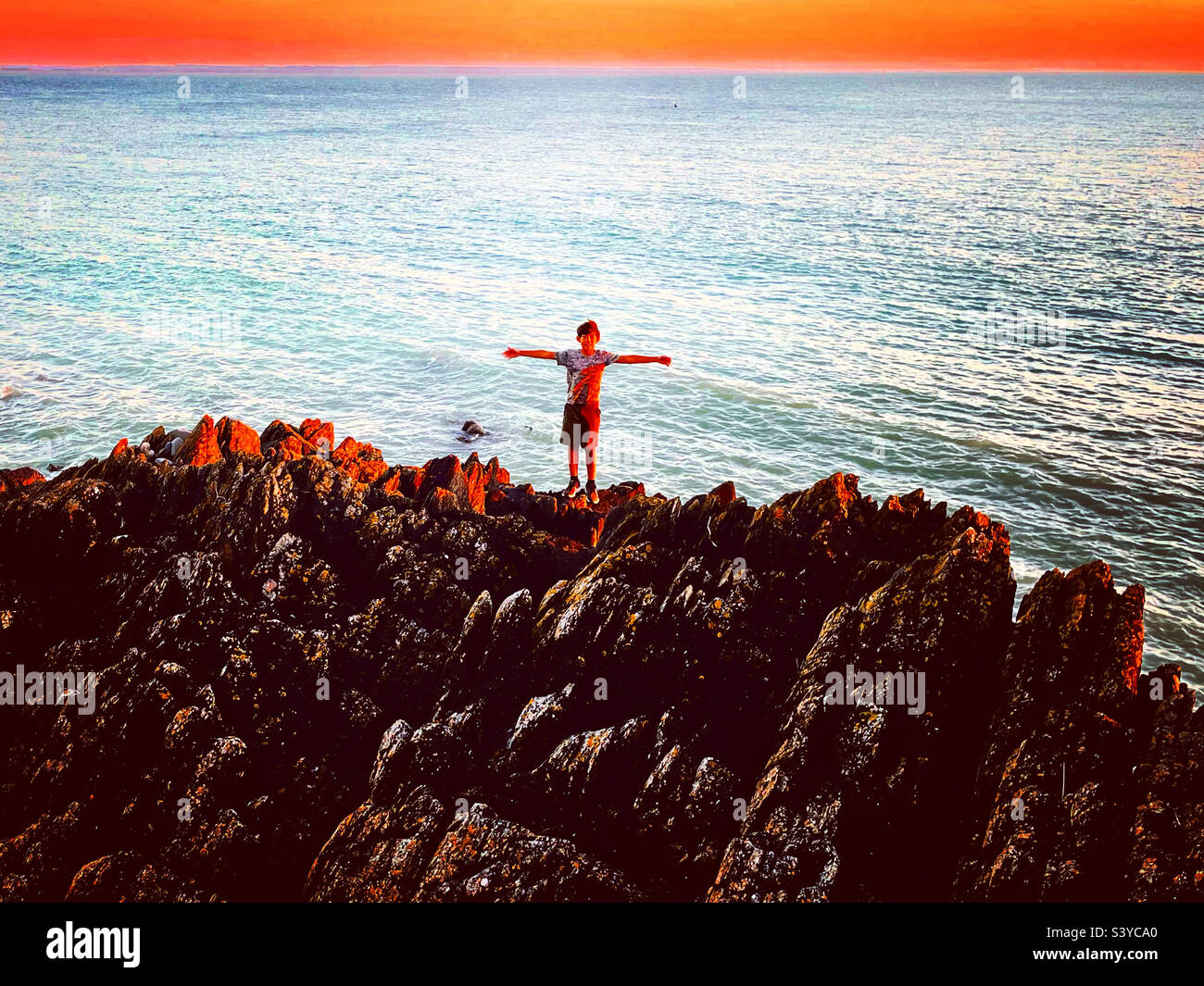 a young boy is having his arm wide open, teady for a hug near the icean ...