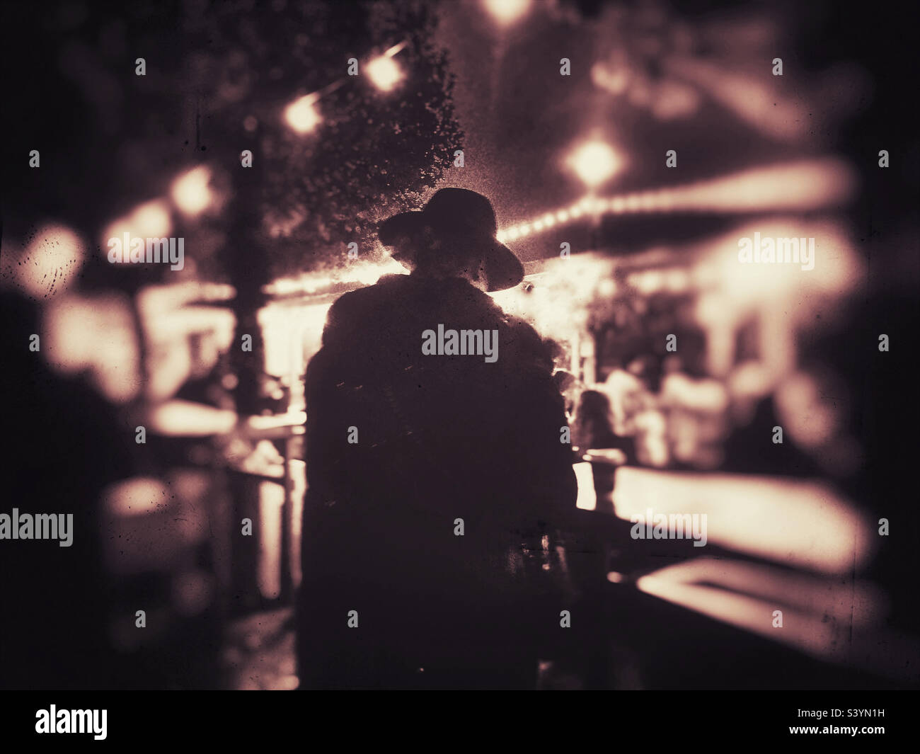 Man with a hat photographed from behind against a cinematic background ...