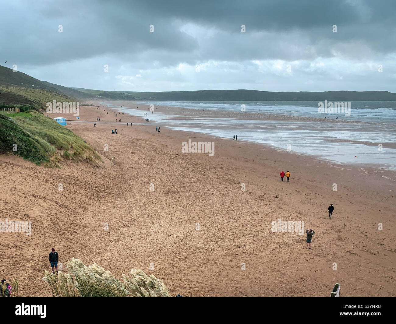 A few visitors enjoy an Autumn walk on Woolacombe beach Stock Photo - Alamy