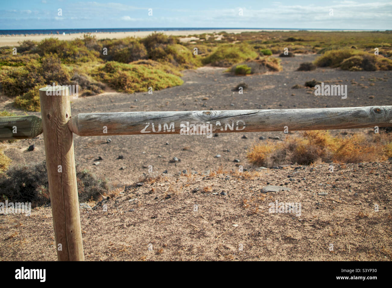 Wooden railing in front of sand dunes with white lettering in German ...