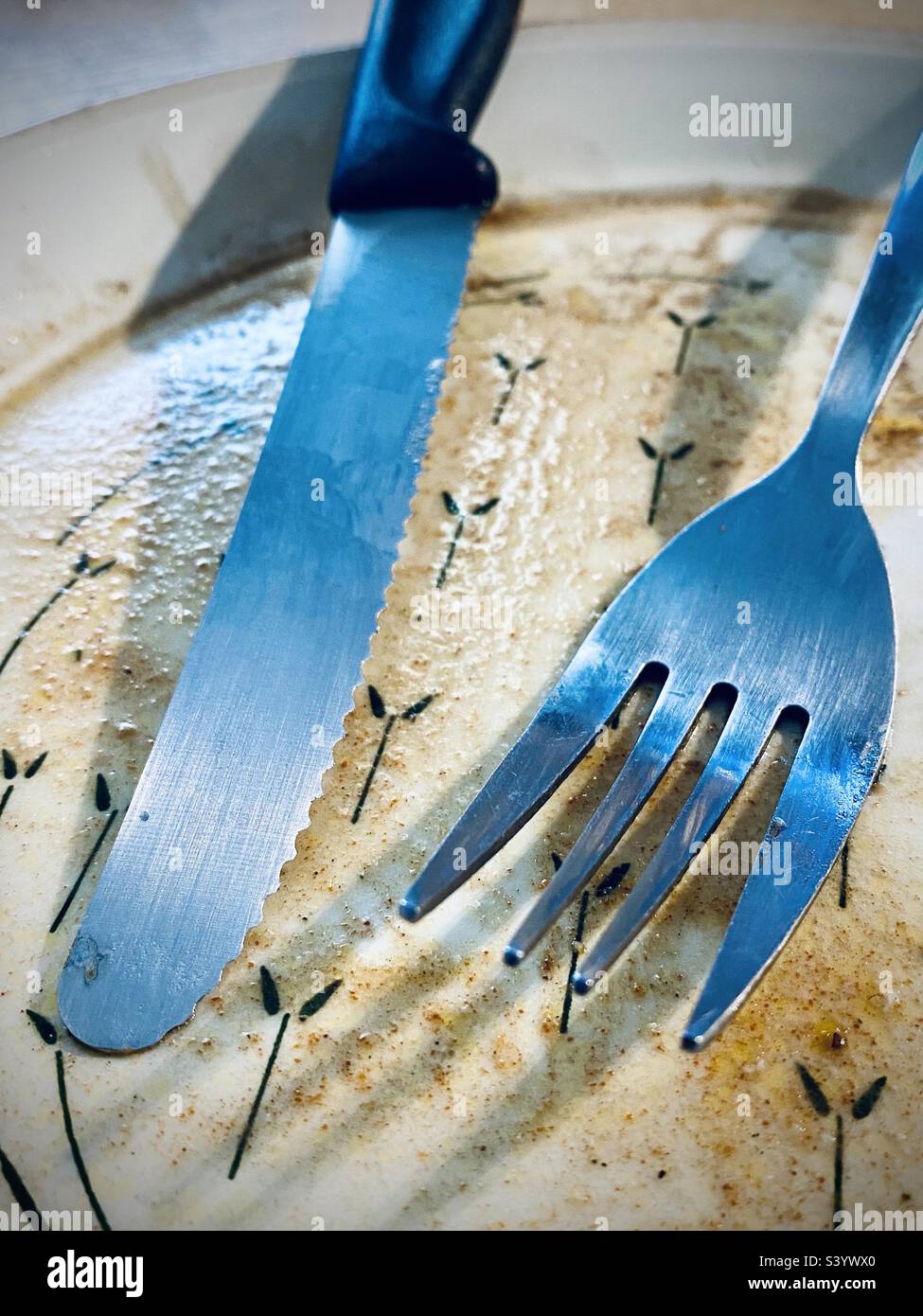 A knife and fork lay on a dirty empty plate Stock Photo - Alamy