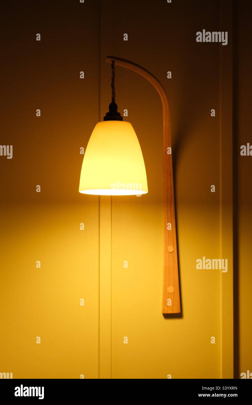 Lit wall light with a wooden fixture Stock Photo - Alamy