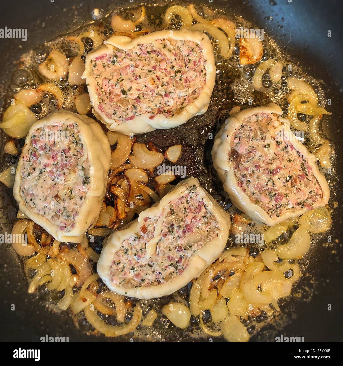 the delicious Swabian speciality Maultaschen fried in a pan with golden ...