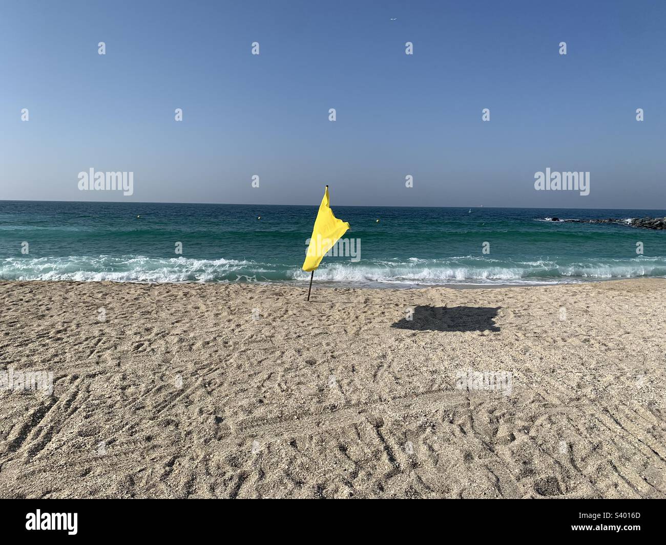 Yellow flag and its shadow on a beach in Dubai, United Arab Emirates ...