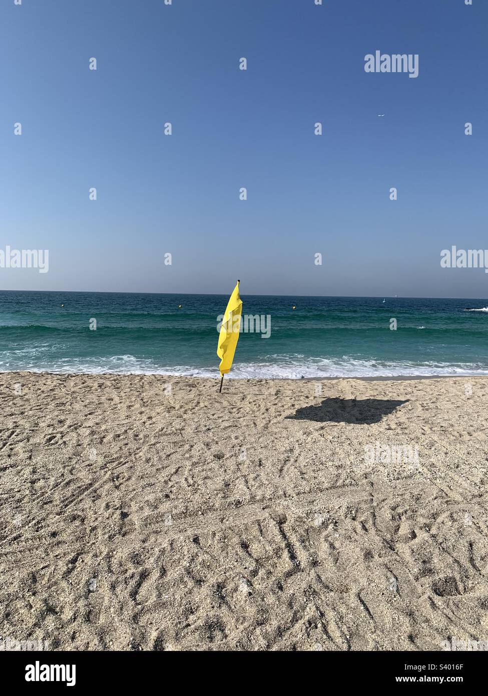 Yellow flag and its shadow on a beach in Dubai, United Arab Emirates ...