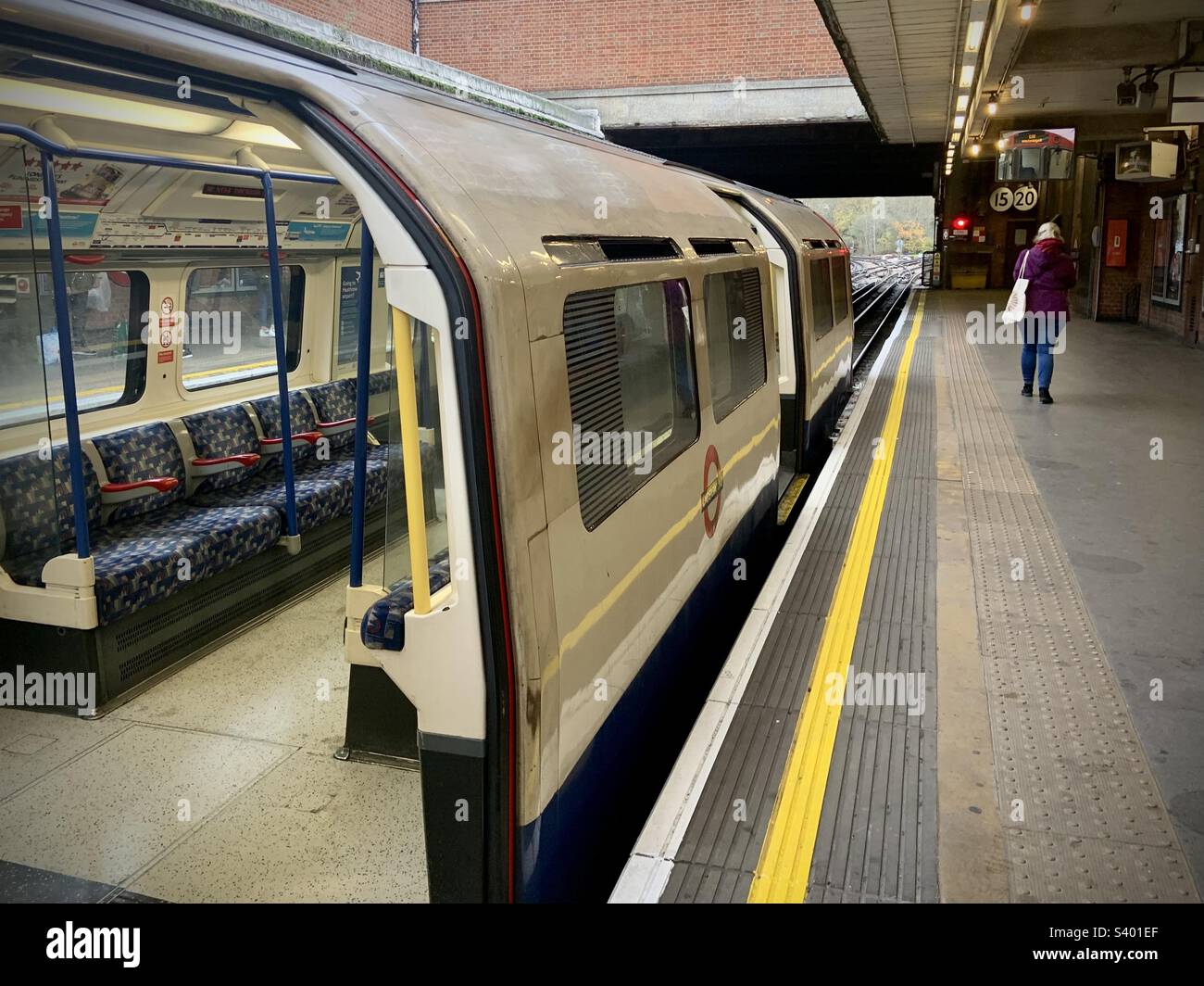 Empty train at station with open doors. One person walking on platform ...