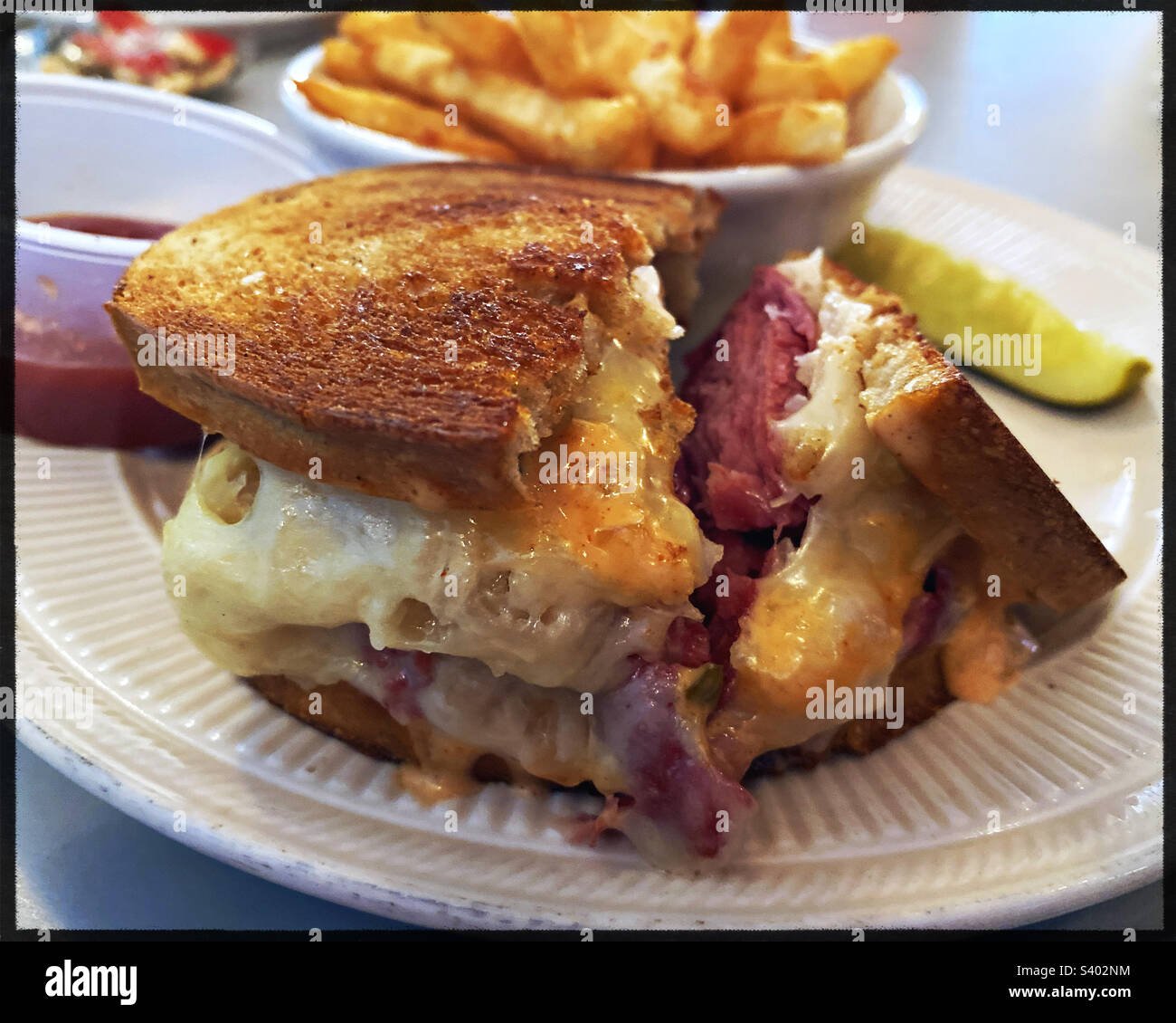 Delicious Rubin sandwich with French fries and a pickle on paper plate ...