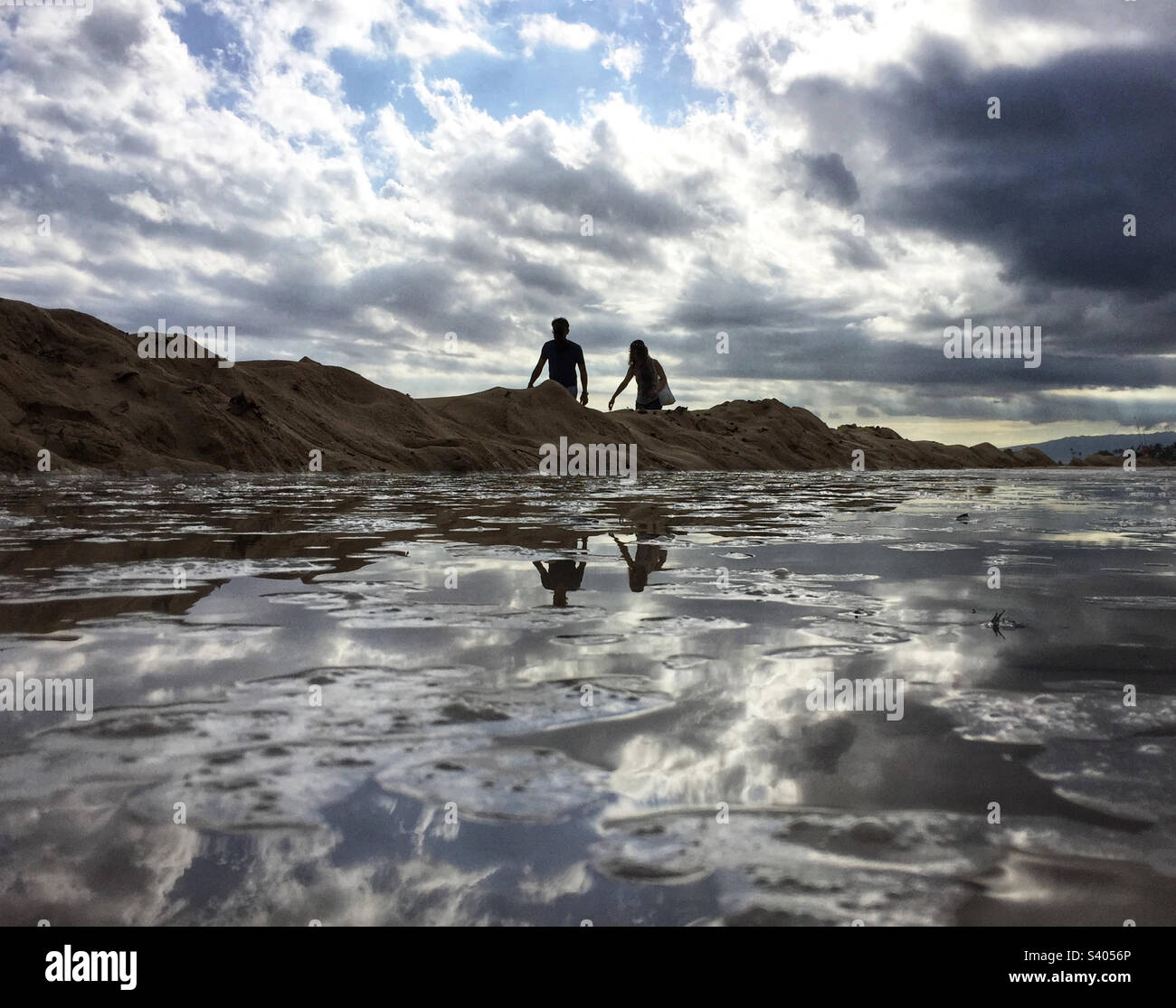Two people walking over sand dunes Stock Photo - Alamy