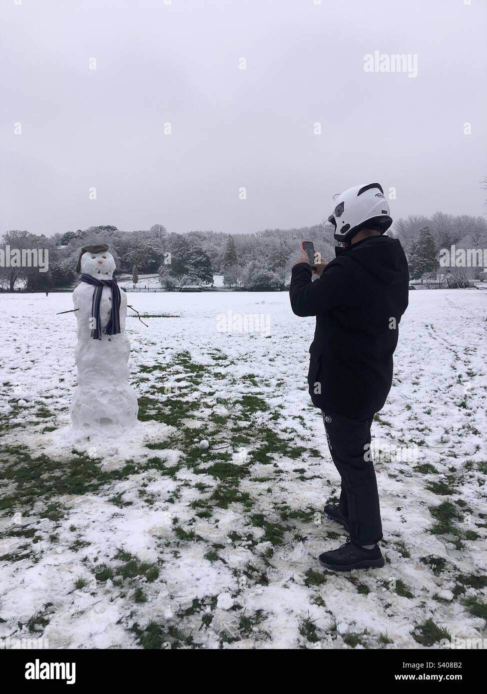Man taking photo of a snowman with his smart phone Stock Photo - Alamy