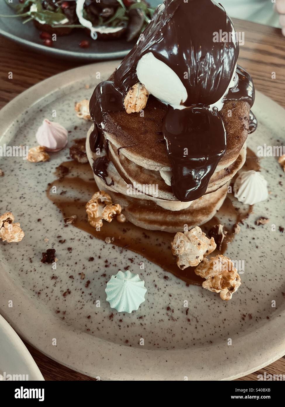 Pancake layers covered with chocolate sauce, cream and popcorn Stock ...