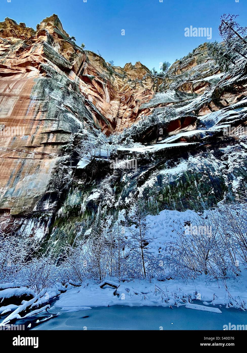 Towering Snow frosted, Icicle fringed, red rock cliff face, water ...