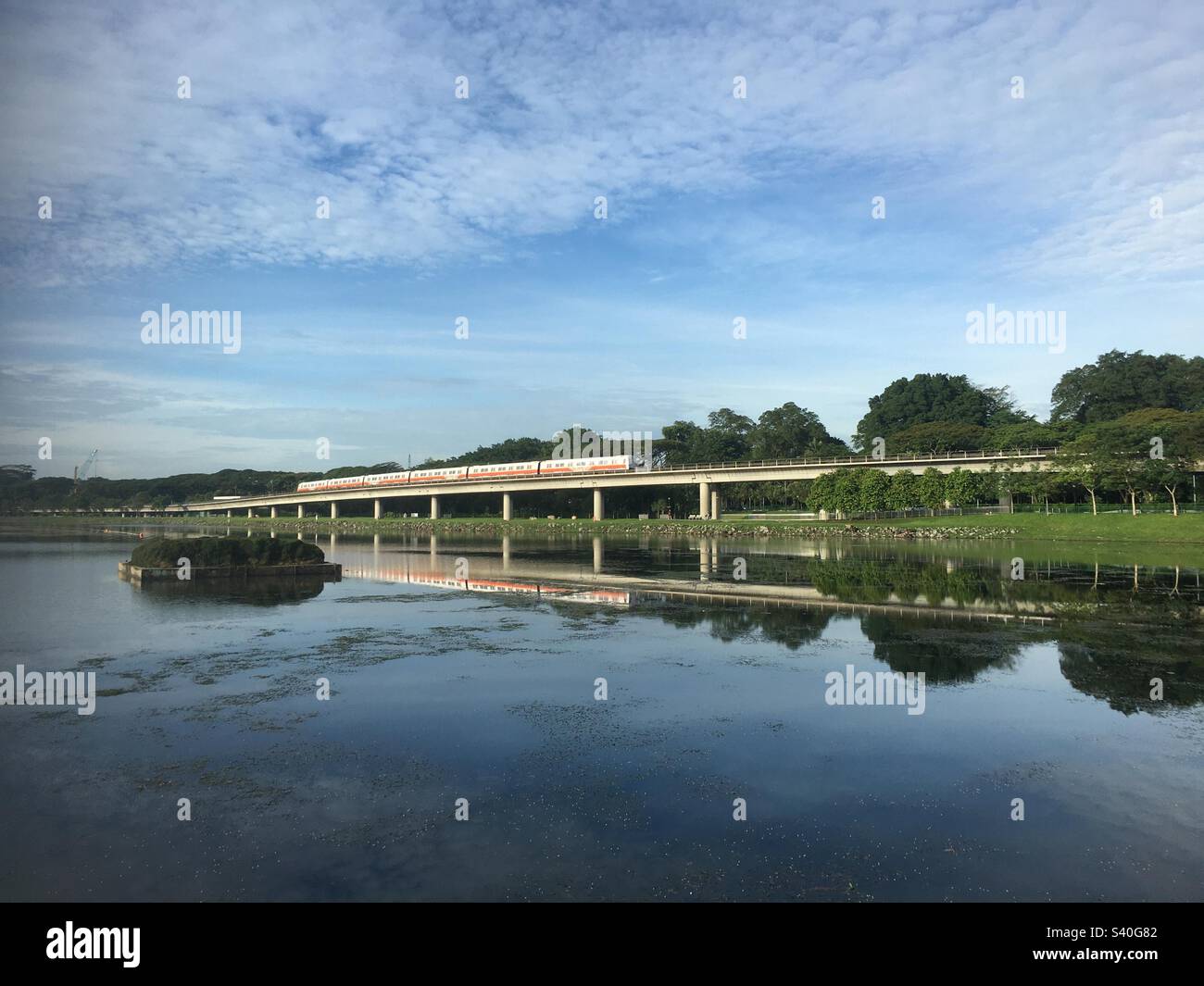 A SMRT train passing by a scenic reservoir in Singapore during morning ...