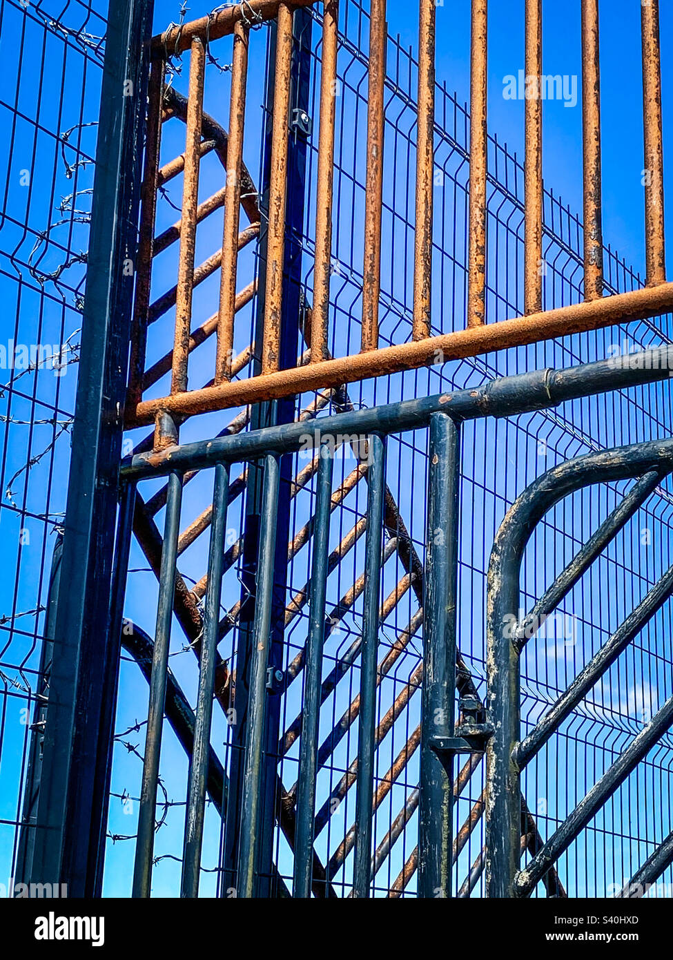 Rusty security fencing topped with barbed wire. A mobile phone photo ...