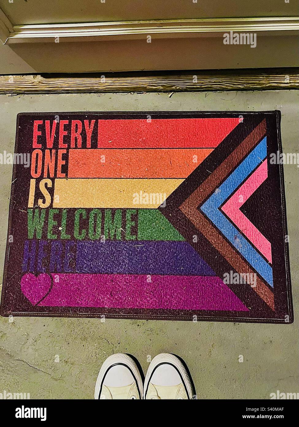 Feet at doorstep with inclusive welcome mat Stock Photo - Alamy