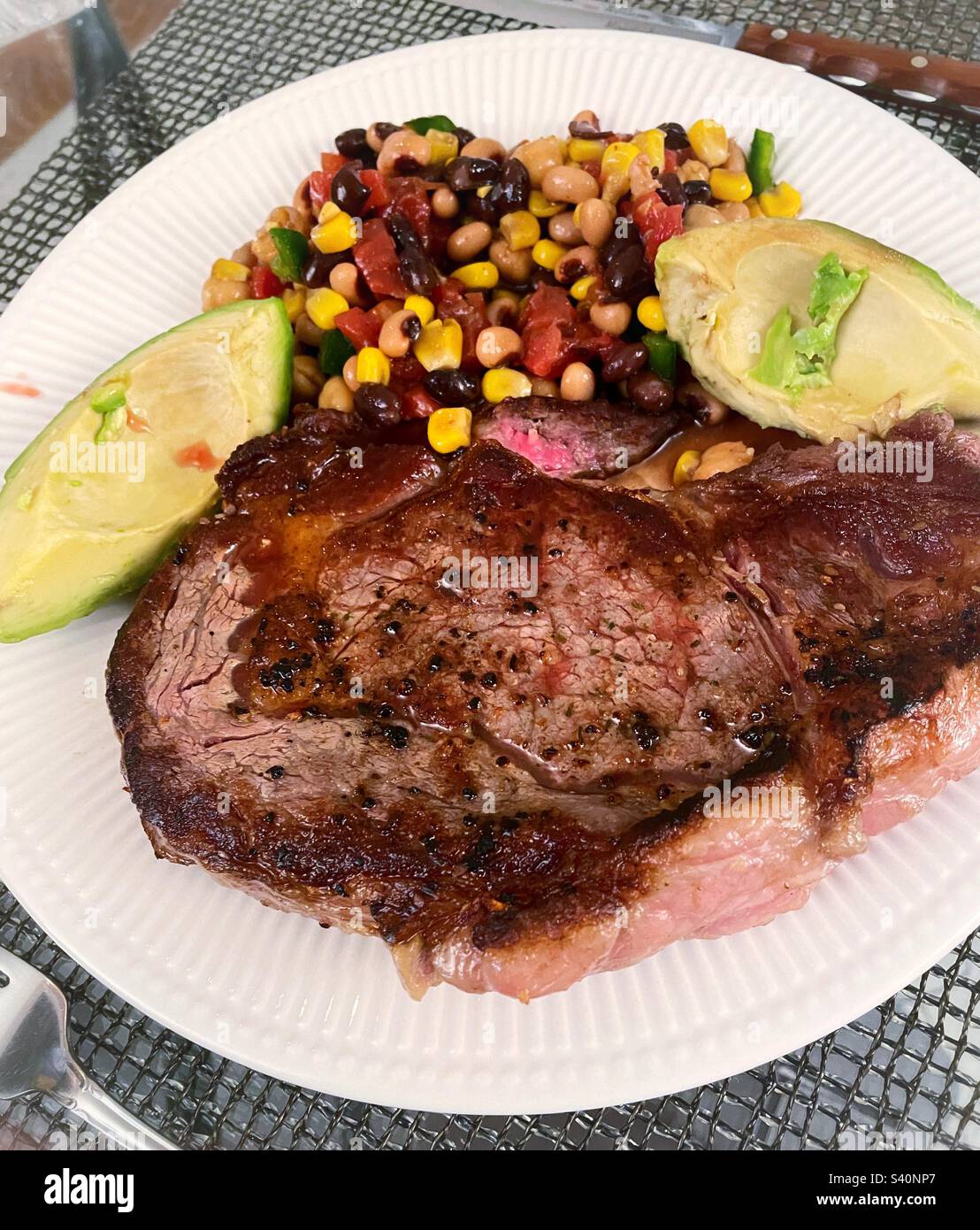 Close up of a plate filled with a grilled ribeye steak, slices of ...