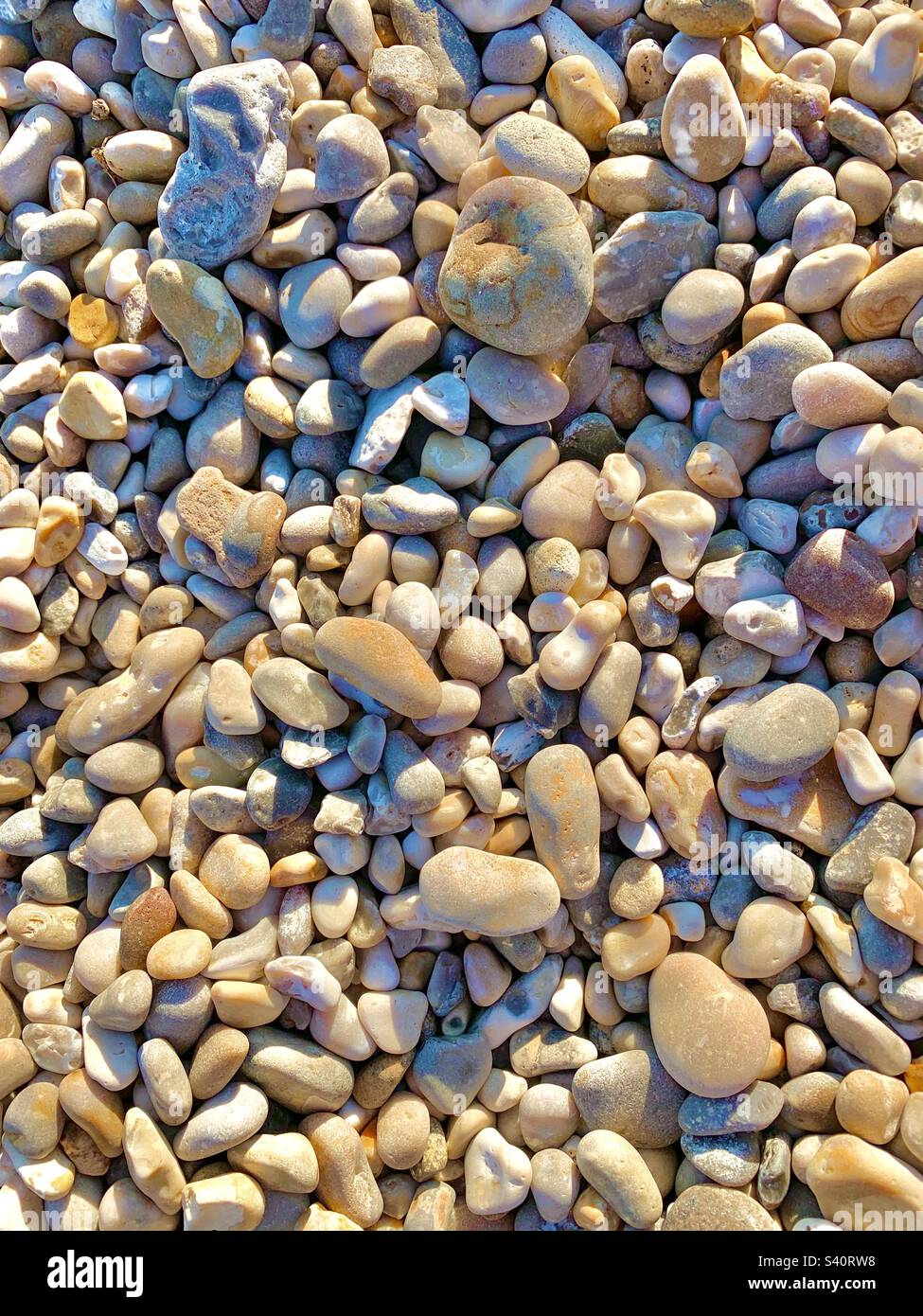 Smooth small multicoloured pebbles close up on a beach in summer in the ...