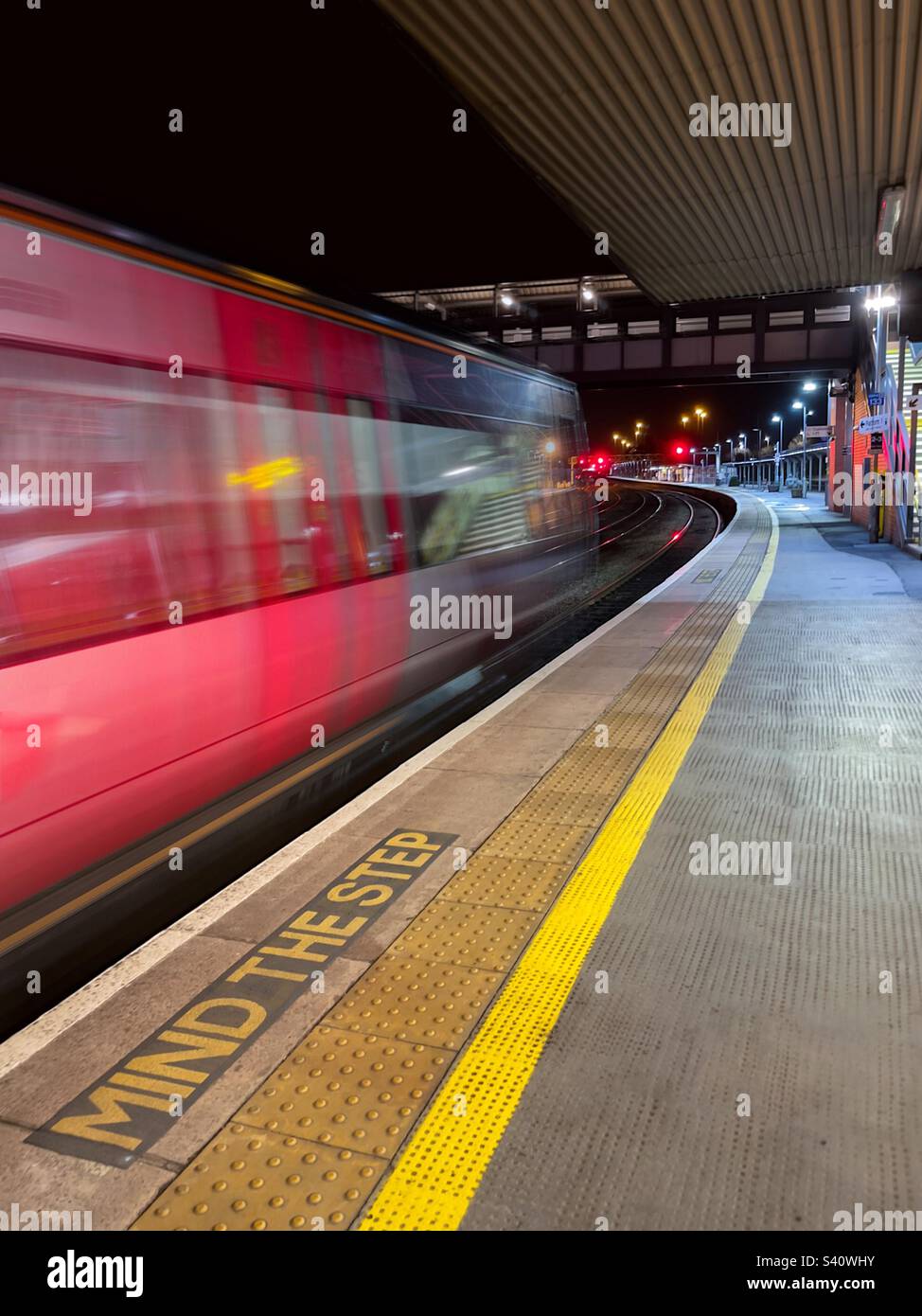 Red train through a station Stock Photo - Alamy