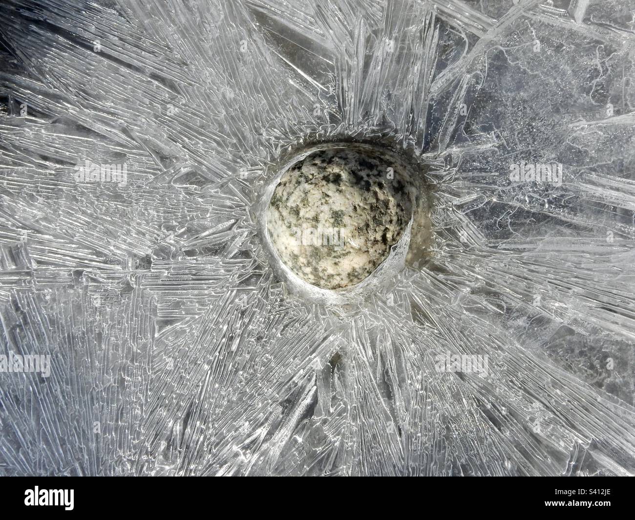 Textured round river rock surrounded by star-like ice formation Stock ...