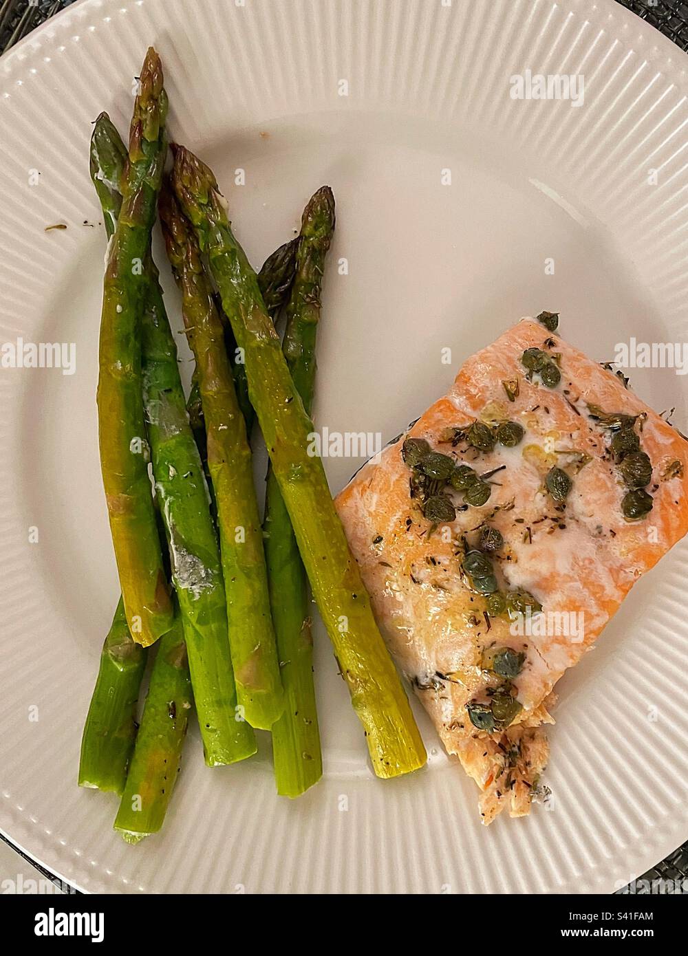 Flat lay of a gourmet entrée of baked salmon fillet in a lemon caper ...